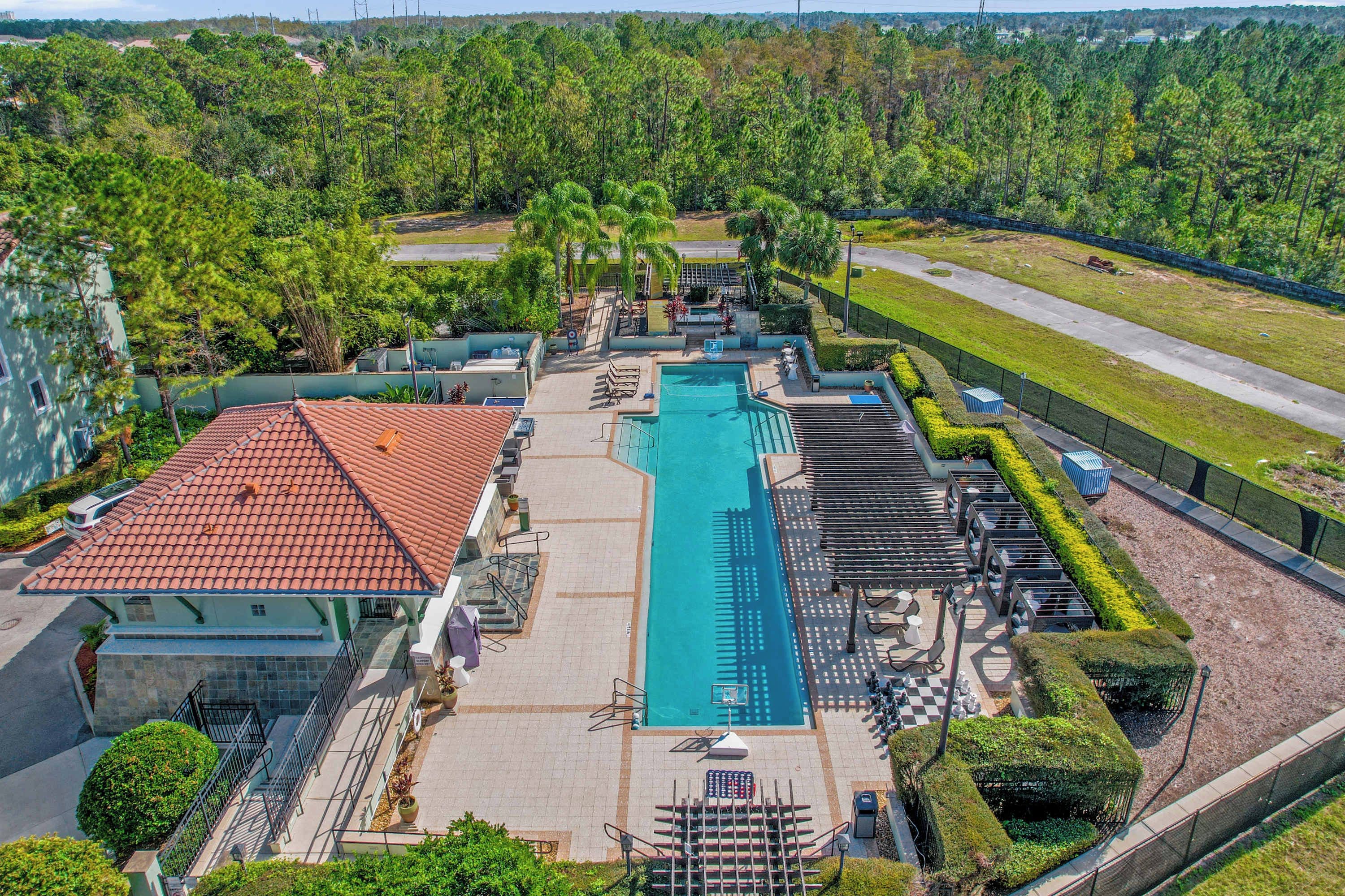 Uma piscina com espreguiçadeiras, uma área de estar coberta e vista para o verde ao redor.