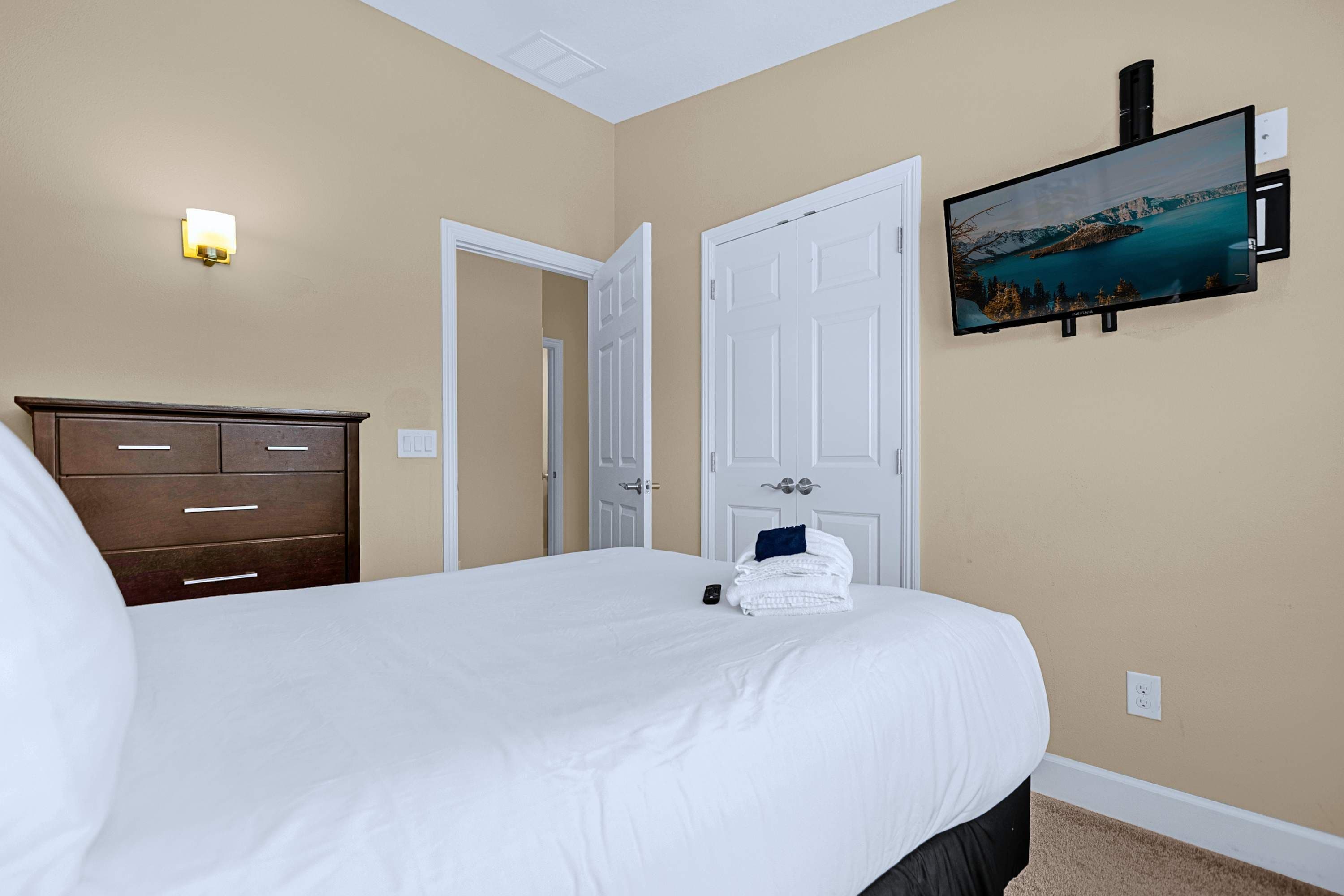 Quarto de hotel com uma cama, cômoda, televisão na parede e uma porta.