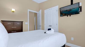 Quarto de hotel com uma cama, cômoda, televisão na parede e uma porta.
