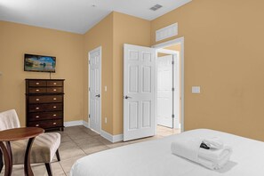 Quarto de hotel com uma cama, uma cadeira, um penteado e duas portas.