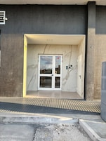 Entrada de um edifício moderno, com porta de vidro, teclado numérico e o número 14 na parede.