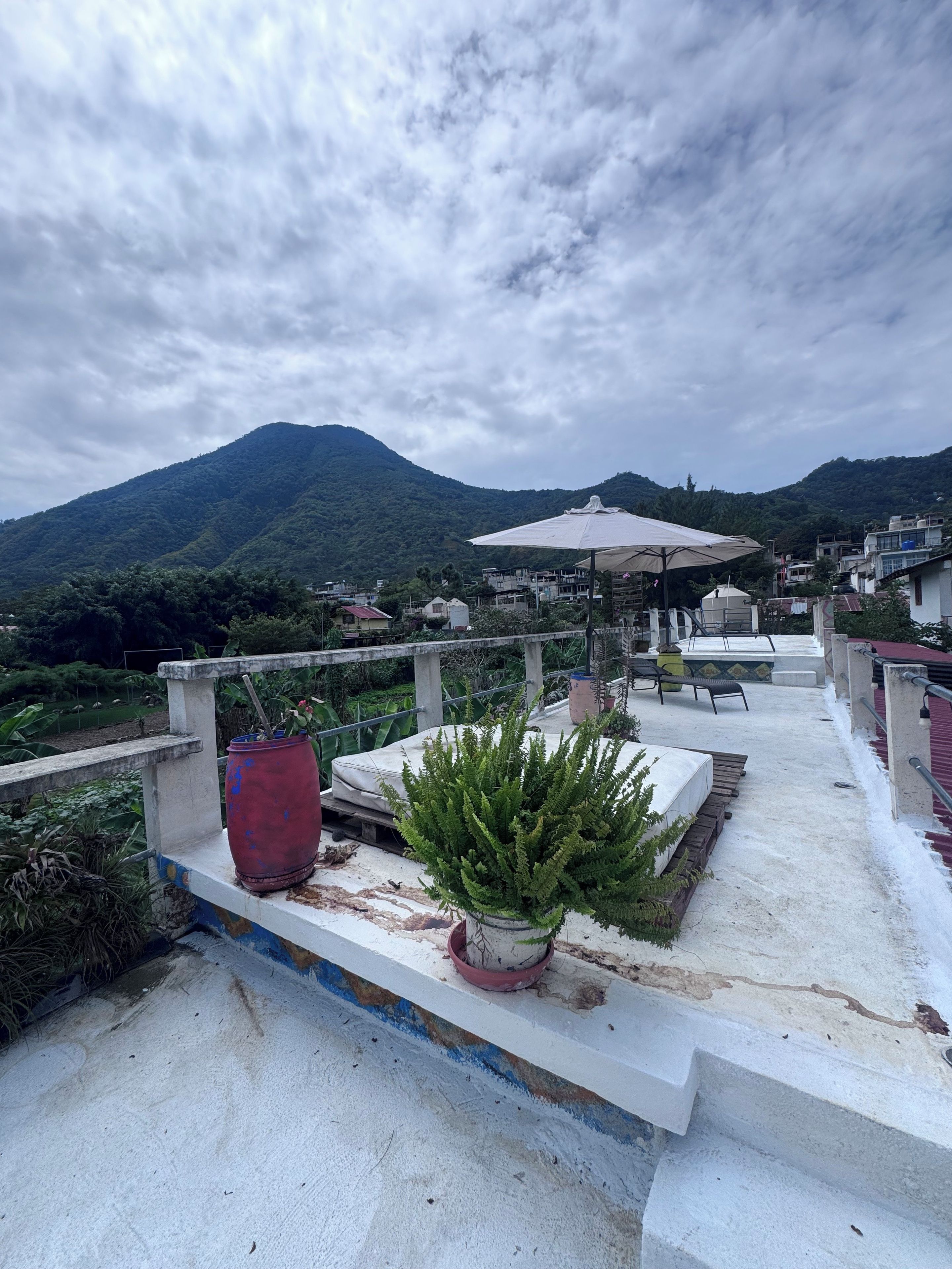 Terraço no telhado com plantas em vasos, móveis de exterior e vista para uma montanha.