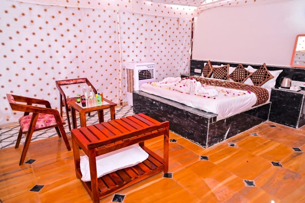 Quarto de hotel com cama, uma mesinha, uma cadeira e ar condicionado.