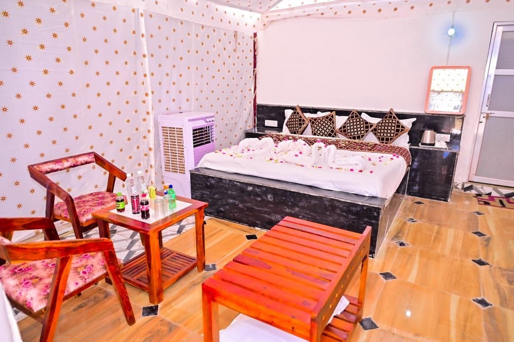 Quarto de hotel com cama, mesa e cadeiras, ar condicionado e espelho na parede.