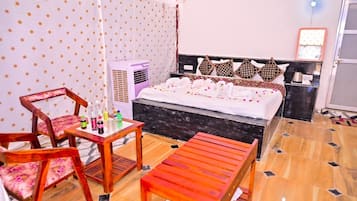 Quarto de hotel com cama, mesa e cadeiras, ar condicionado e espelho na parede.