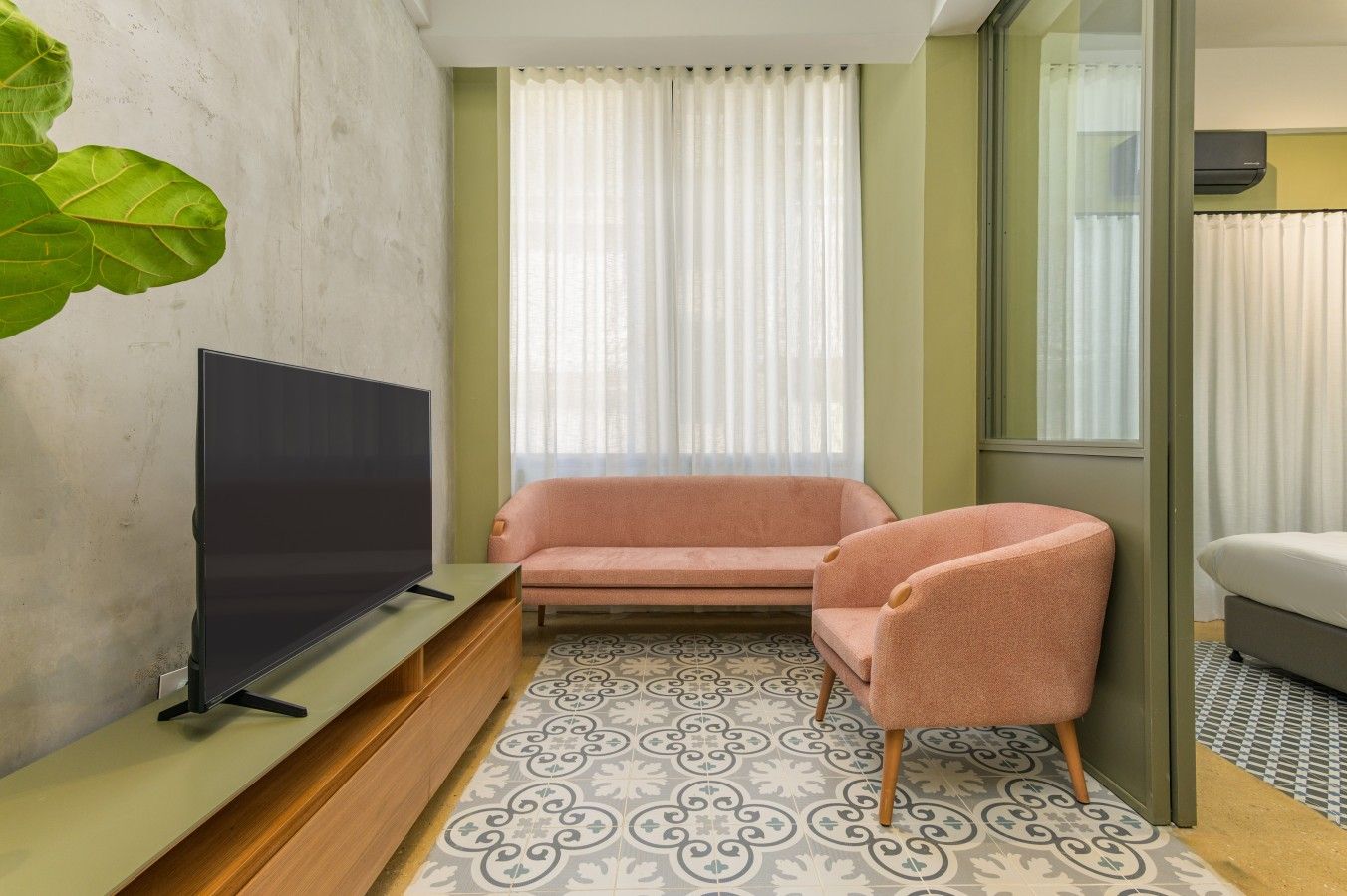 Uma sala de estar moderna com uma TV de tela plana, um sofá rosa e um piso estampado.