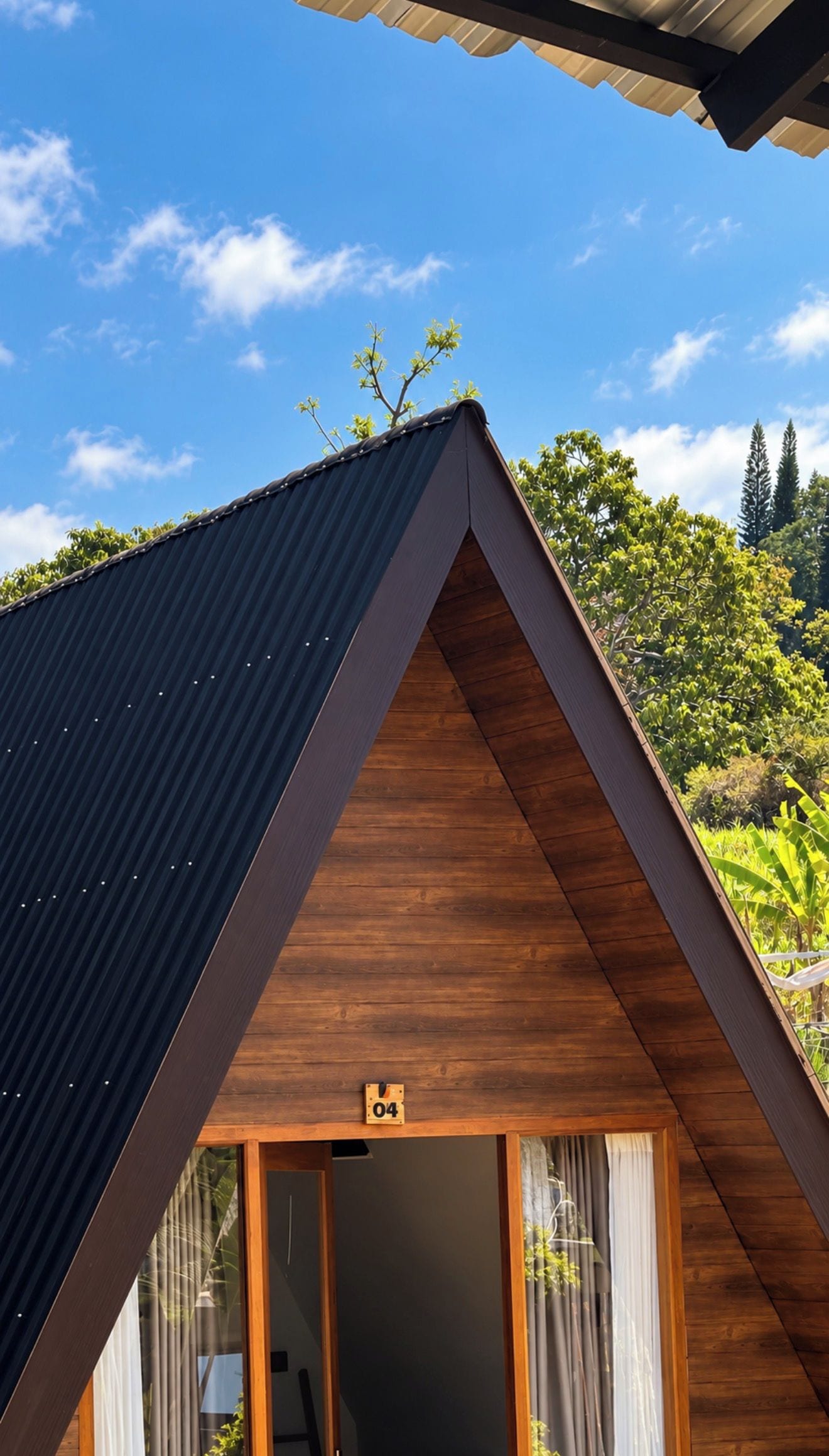 Um edifício moderno com telhado inclinado, fachada de madeira e a placa com o número '04'.