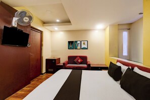 Quarto de hotel com cama, escrivaninha, cadeira, televisão e obras de arte na parede.