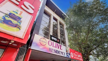 Um edifício com a placa Olive Residency, um hotel de classe executiva, e uma loja de chá chamada Tea Super.