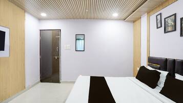 Um quarto com uma cama, uma porta, um espelho e quadros na parede.