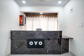 Bancada de recepção com uma placa indicando 'OYO' no hall moderno de um hotel.