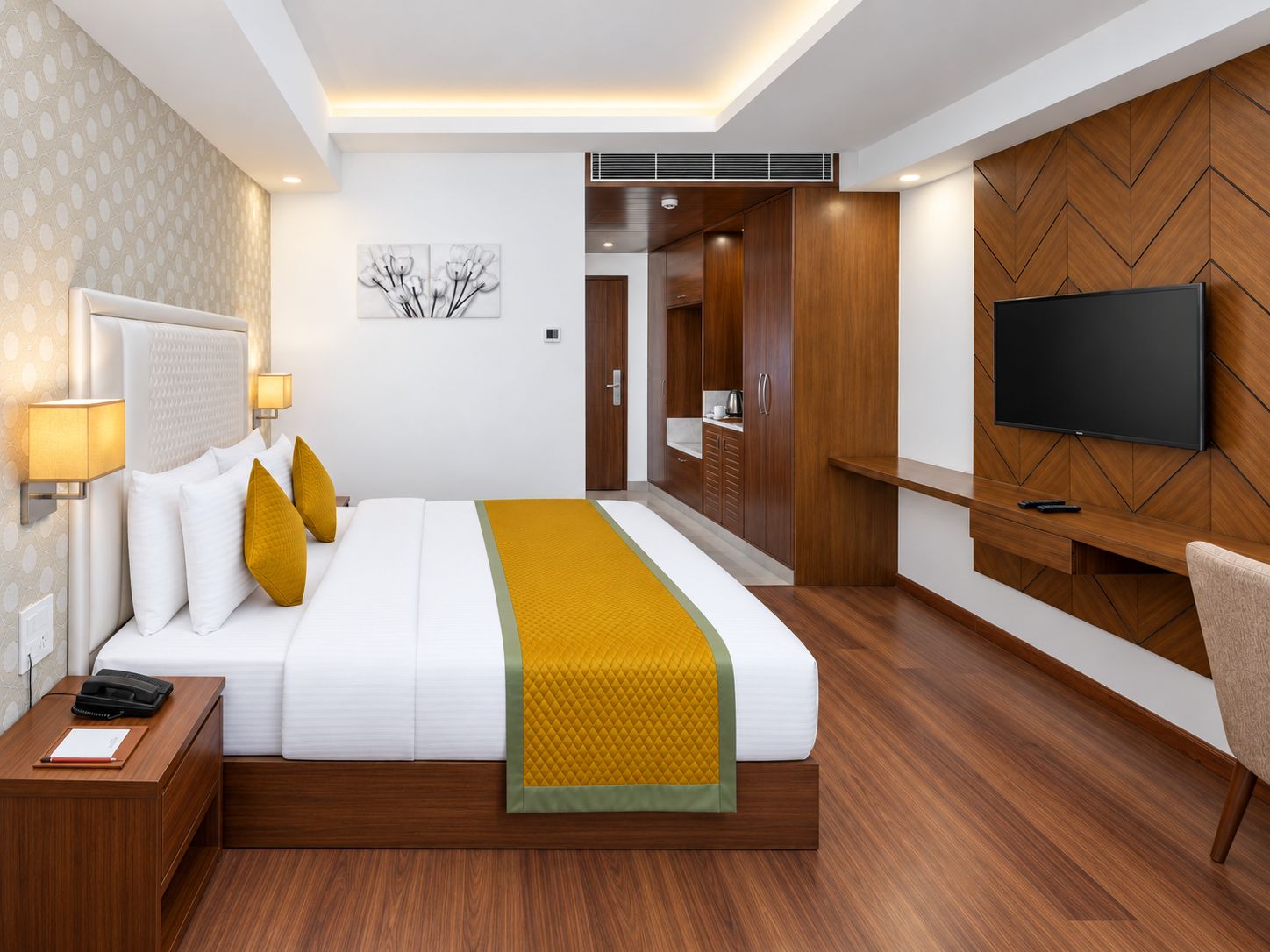 Quarto de hotel com cama, luminárias de cabeceira, televisão, guarda-roupa e porta do banheiro.