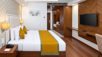 Quarto de hotel com cama, luminárias de cabeceira, televisão, guarda-roupa e porta do banheiro.