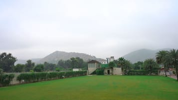 Campo gramado com um edifício e uma montanha ao fundo.