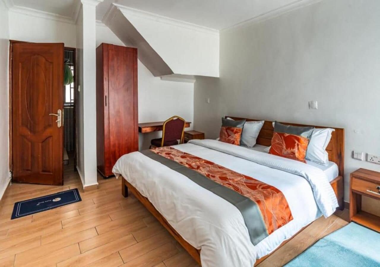 Quarto com cama grande, cabeceira de madeira e mesa de cabeceira.