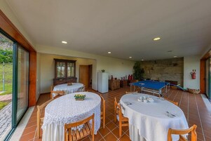 Uma área de refeições com mesas redondas, mesa de bilhar e parede de pedra.