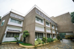 Um edifício de vários andares com telhado plano, janelas amplas e um pátio pavimentado.