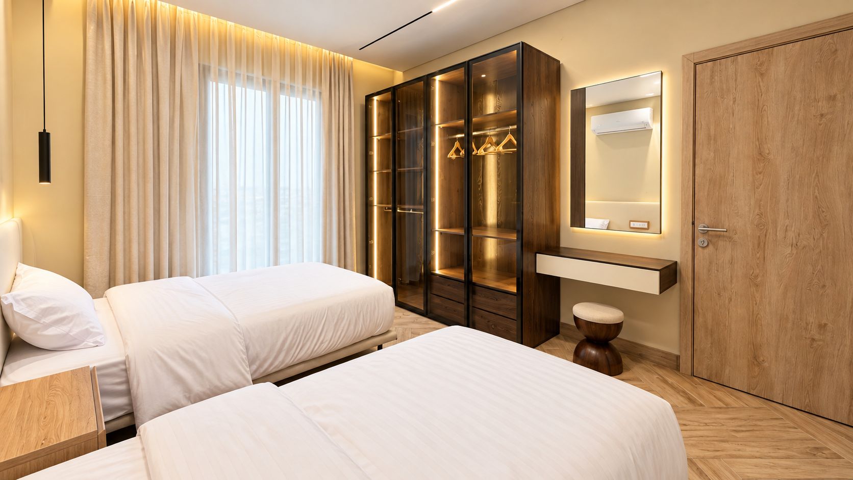 Quarto de hotel com duas camas, um guarda-roupa, uma toucador com espelho e um banquinho.