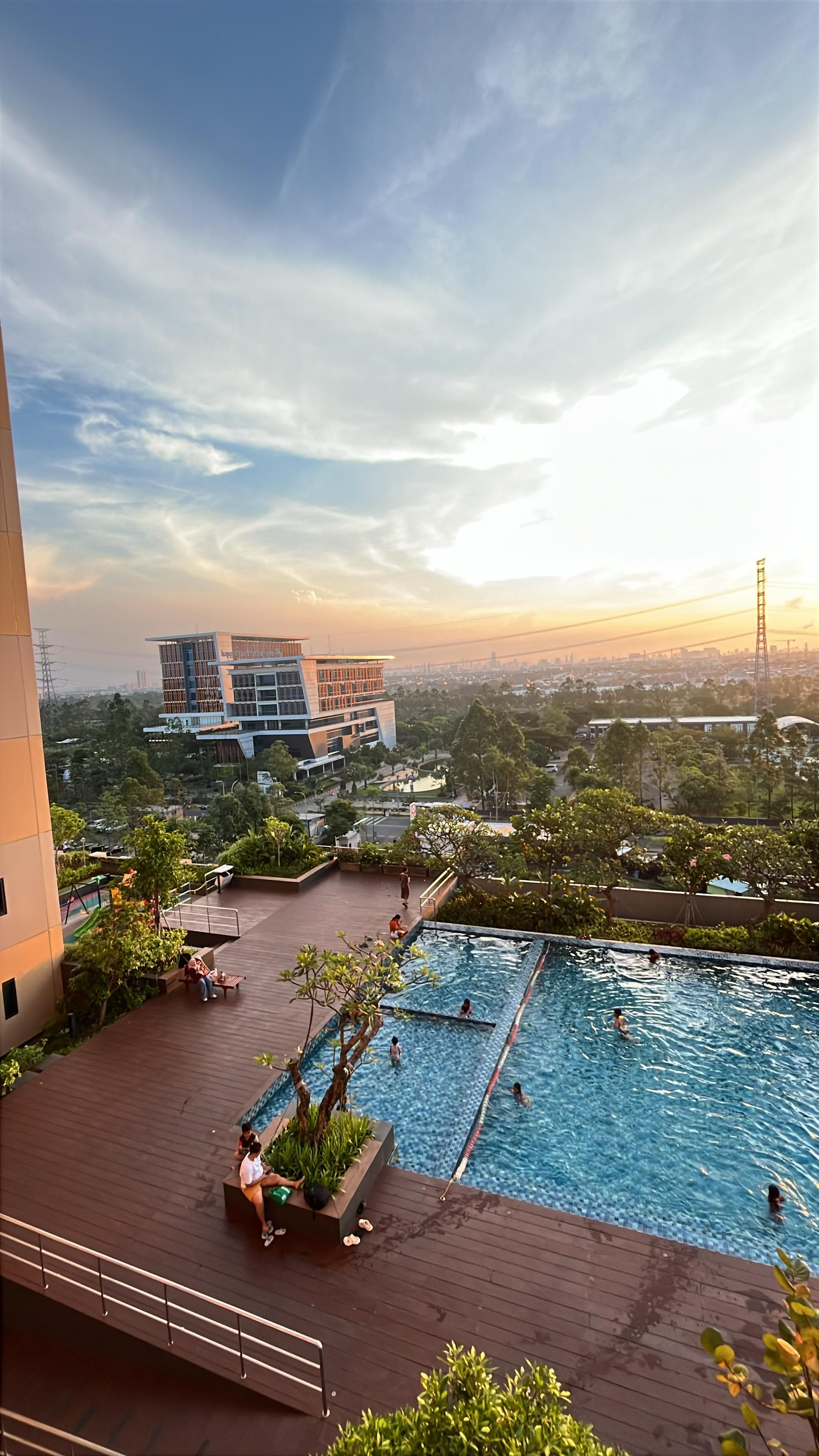Piscina no terraço com vista para o horizonte urbano e um edifício moderno ao fundo.