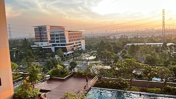 Piscina no terraço com vista para o horizonte urbano e um edifício moderno ao fundo.