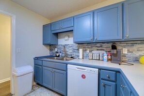 Cozinha com armários azuis, lava-louças, pia e painel de azulejos.