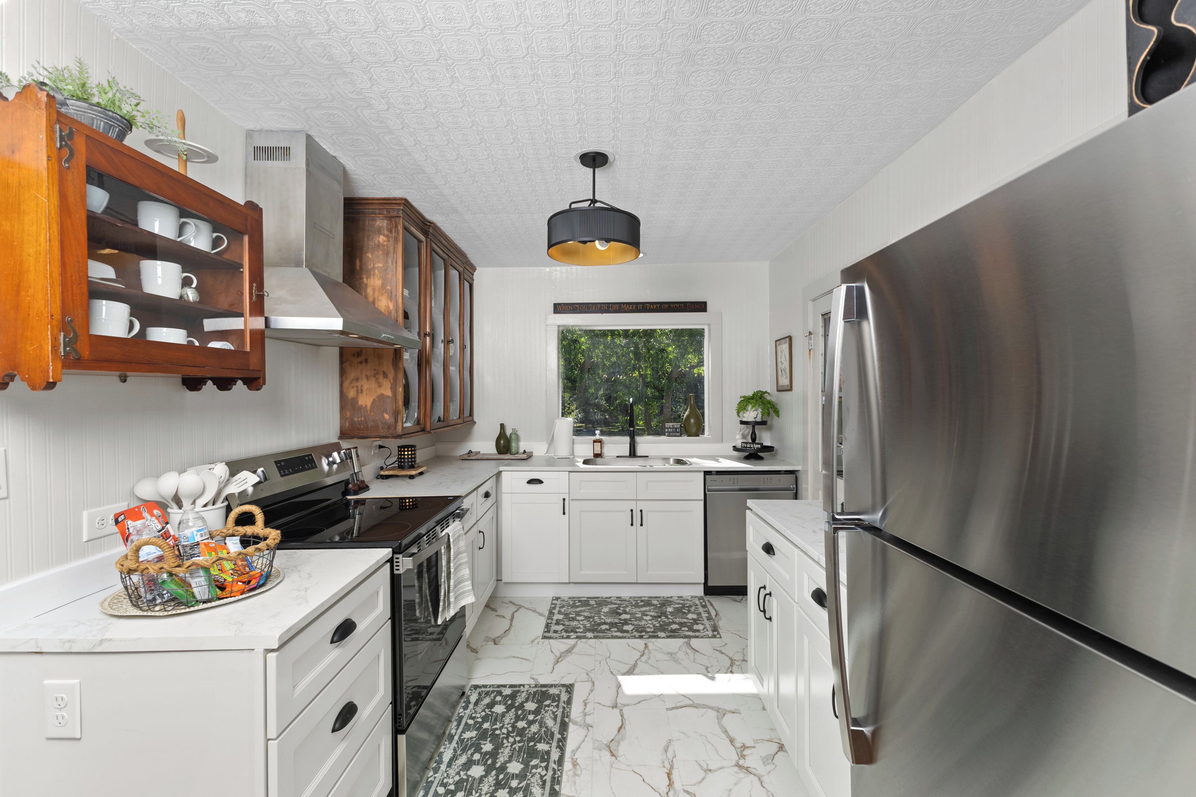 Cozinha moderna com armários brancos, eletrodomésticos de aço inoxidável e teto decorativo.