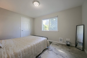 Quarto com cama, janela, porta e espelho.