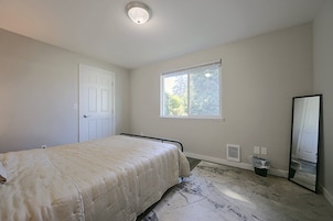 Quarto com cama, janela, porta e espelho.