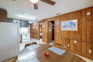 Uma área de refeições com uma mesa de madeira, cadeiras e um ventilador de teto.