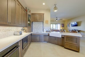 Cozinha moderna com armários de madeira, painel de azulejos e forno embutido.