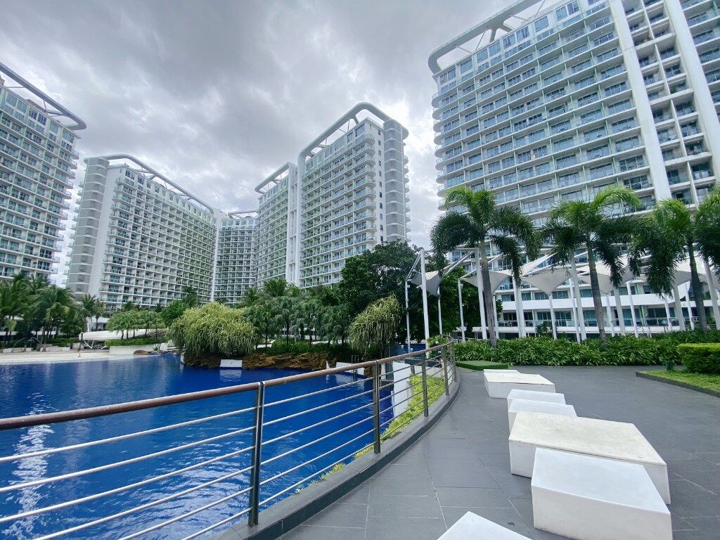 Um moderno complexo residencial com piscina, varandas brancas e vegetação exuberante.