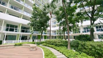 Hotel com vários andares e pátio central com um caminho curvo, palmeiras e diversos arbustos.