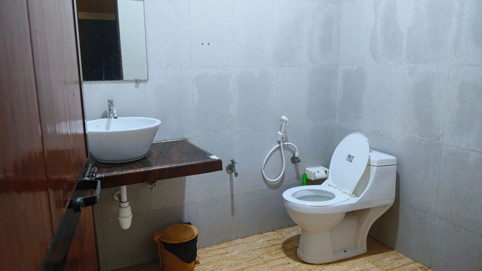 Casa de banho pequena com lavatório branco, sanita e chão em madeira.