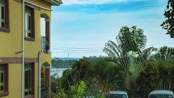 Edifício amarelo com varanda, um carro estacionado e uma palmeira ao primeiro plano.