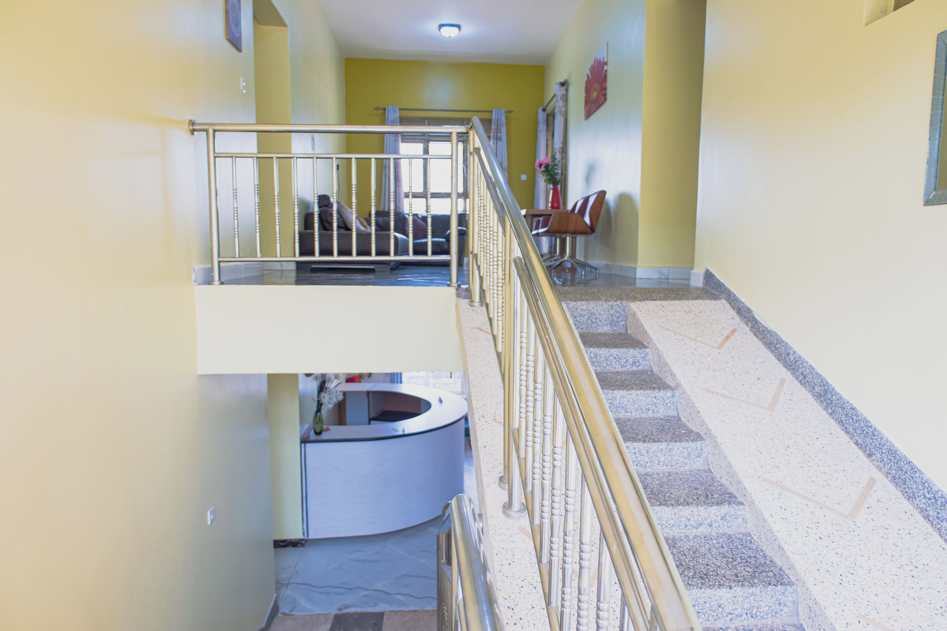 Espaço interior em vários níveis, com escadaria, balcão de recepção e área de estar.