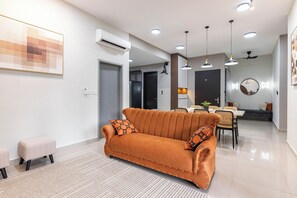 Uma sala de estar moderna com sofá, área de refeições e cozinha ao fundo.