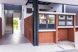 Um edifício moderno com escada que leva a um andar superior, porta de garagem e fachada de tijolos com caixas de correio numeradas.
