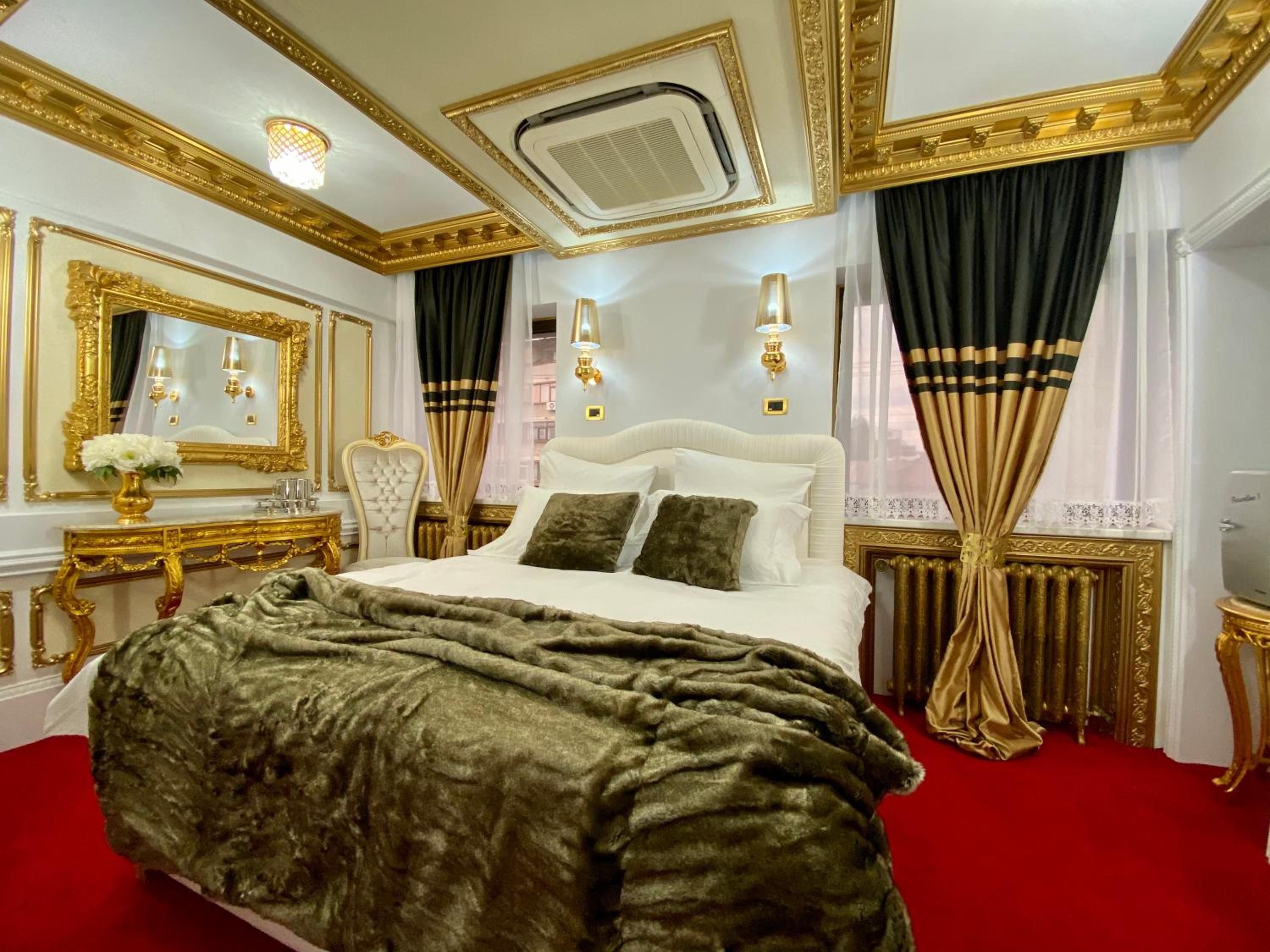 Um quarto luxuoso com uma cama grande, espelhos dourados ornamentados e cortinas elegantes.