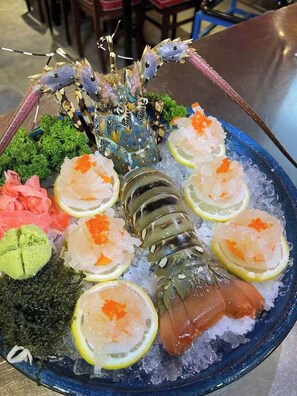 Prato de frutos do mar com diversos tipos de peixes e mariscos, incluindo camarão e salmão, servido sobre uma base de gelo.