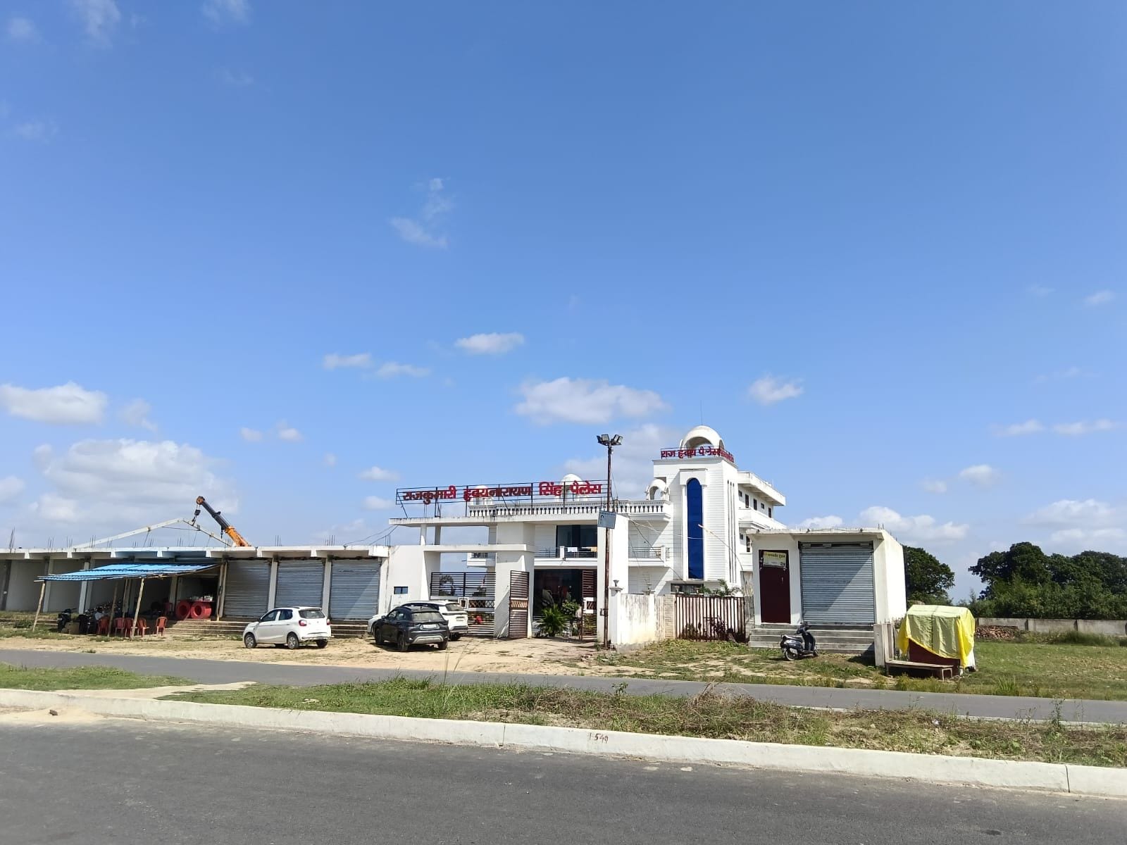 Edifício comercial com placa, área de estacionamento coberta e rua em frente.