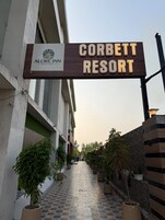 Placa do Resort Corbett com um caminho ladeado por plantas em vasos.