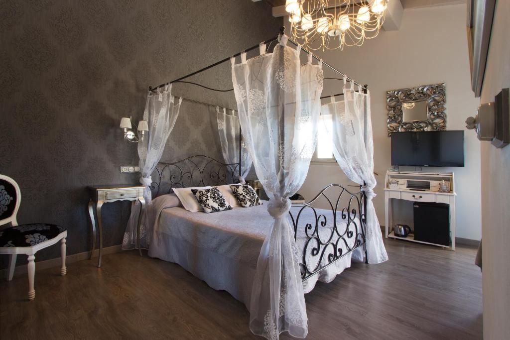Quarto com cama de dossel, mesa de cabeceira, uma cadeira, televisão e armário.