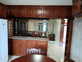 Cozinha com armários de madeira, bancada de granito e área de refeições com mesa e cadeiras.