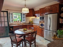 Cozinha com armários de madeira, geladeira de aço inoxidável e mesa de jantar com cadeiras.