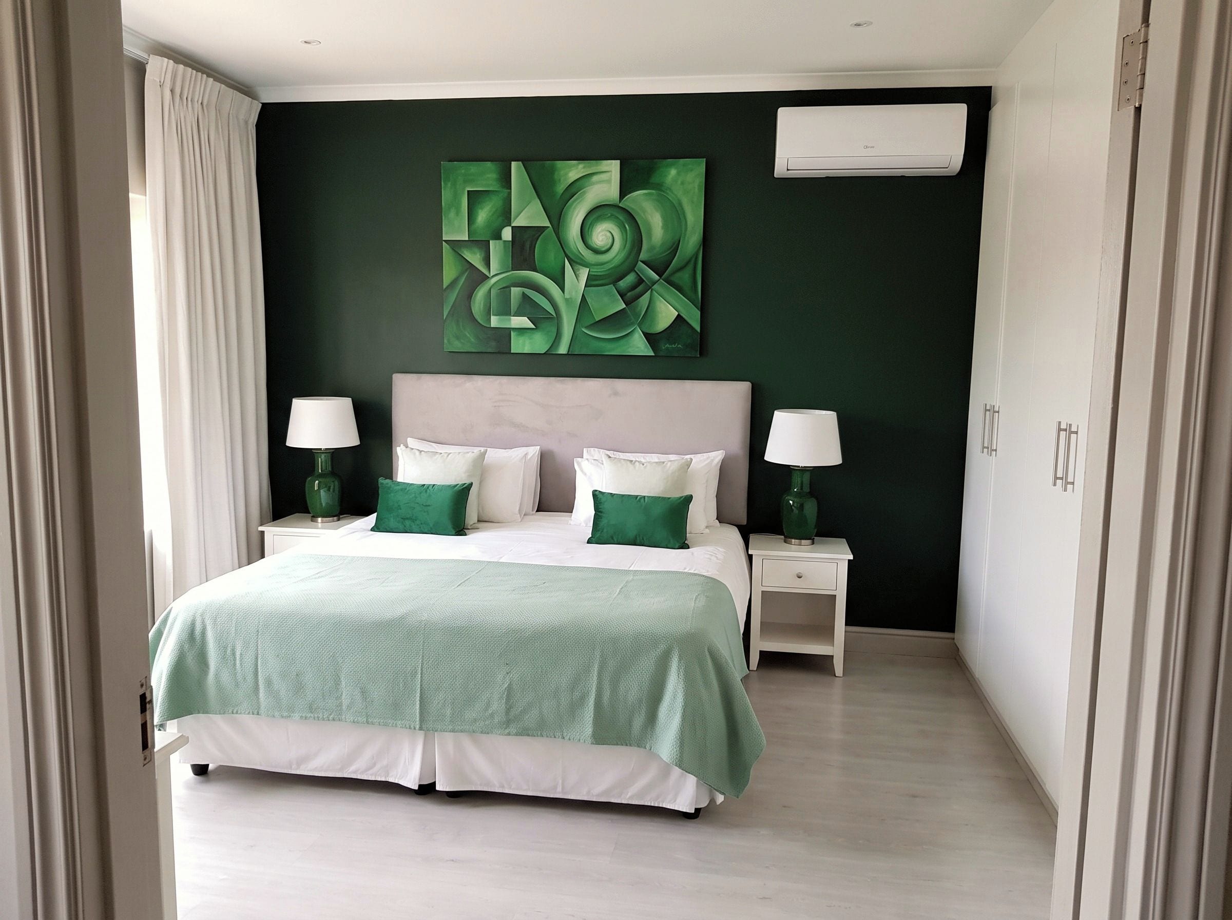 Quarto com cama, duas mesas de cabeceira, ar-condicionado fixado na parede e um quadro abstrato verde.