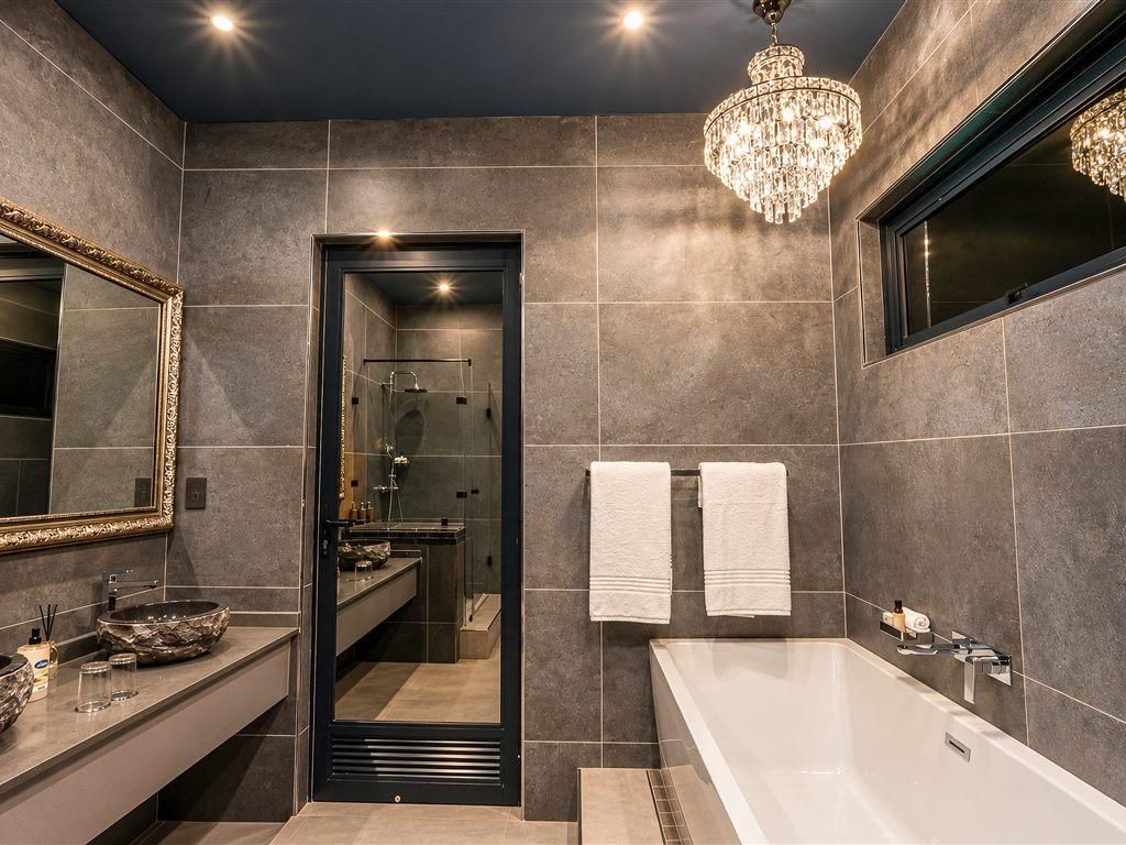 Uma casa de banho moderna com um espelho grande, uma banheira e um candeeiro.