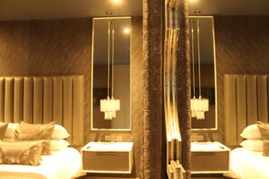 Quarto de hotel com uma cama grande, mesa de cabeceira, espelho e lustre.