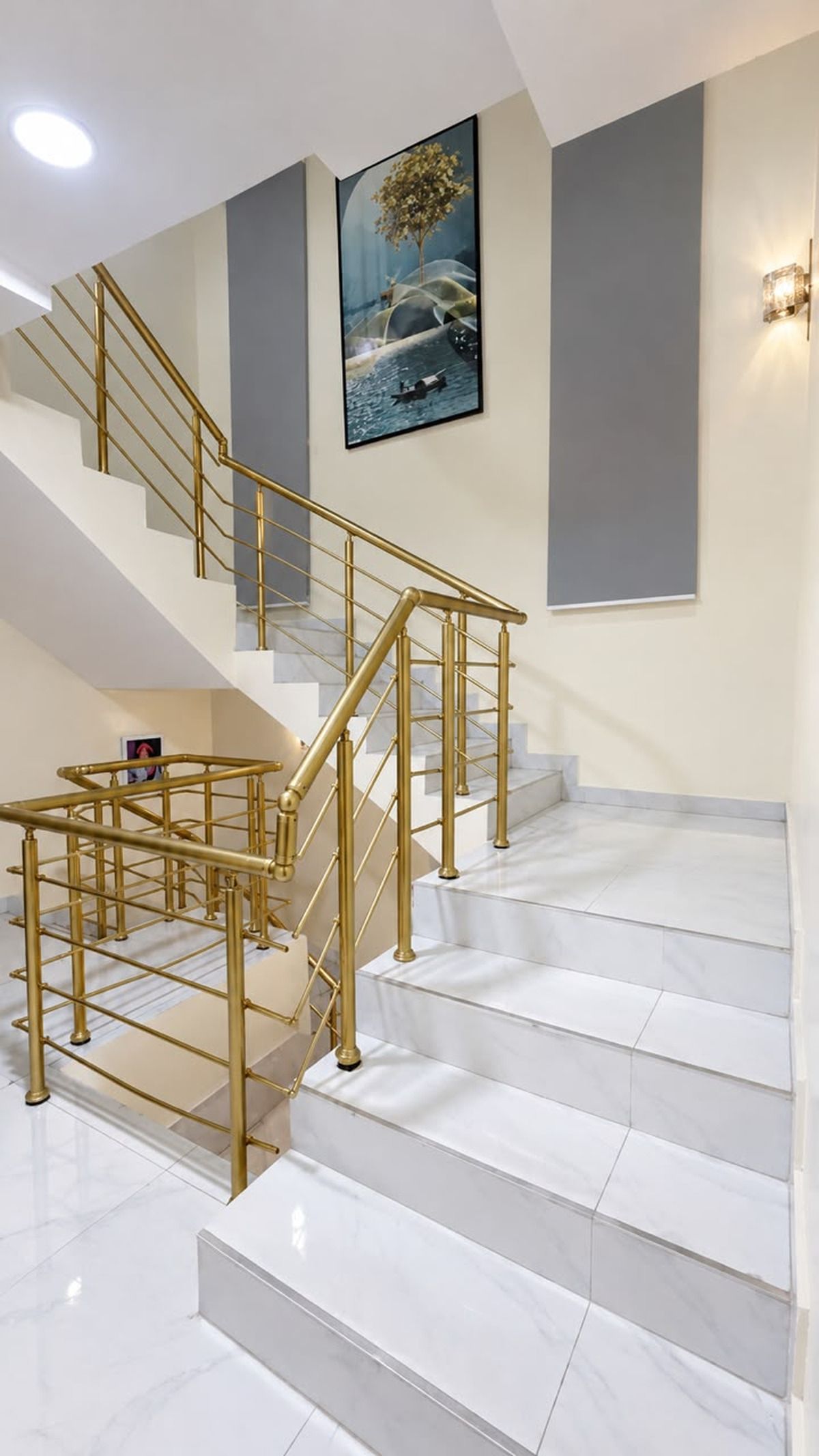 Uma escadaria com corrimão dourado e degraus brancos.