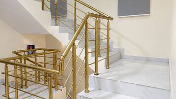 Uma escadaria com corrimão dourado e degraus brancos.