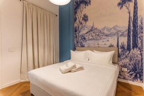 Quarto de hotel com cama, cortina, painel decorativo na parede e piso de madeira.